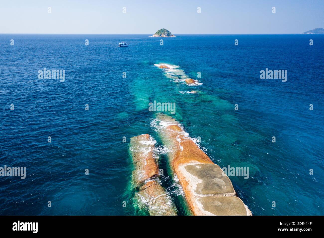 Aerial view of a dive boat near a narrow tropical coral reef and small ...