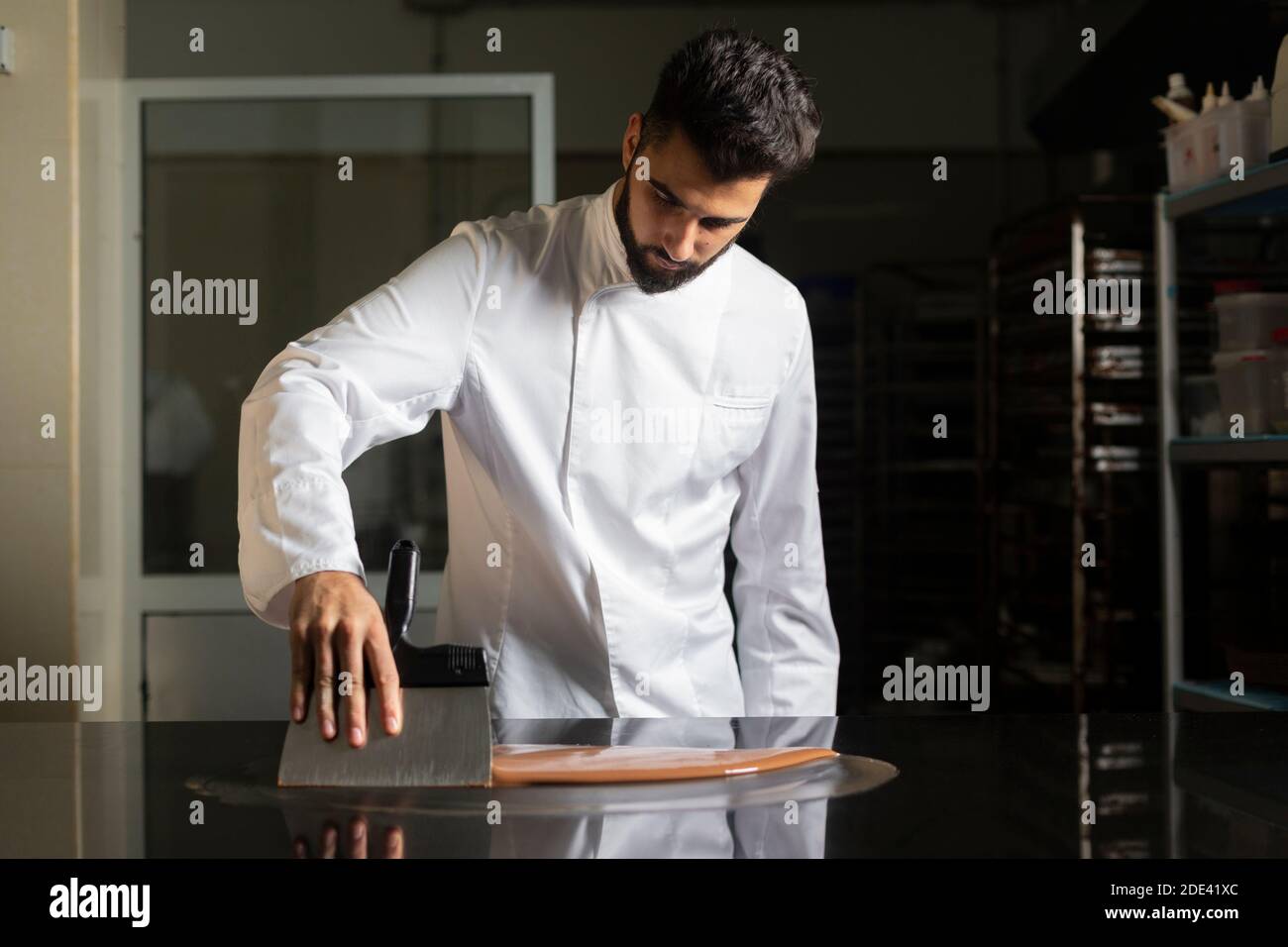 Pastry chef working on tempering chocolate on marble table Stock Photo ...