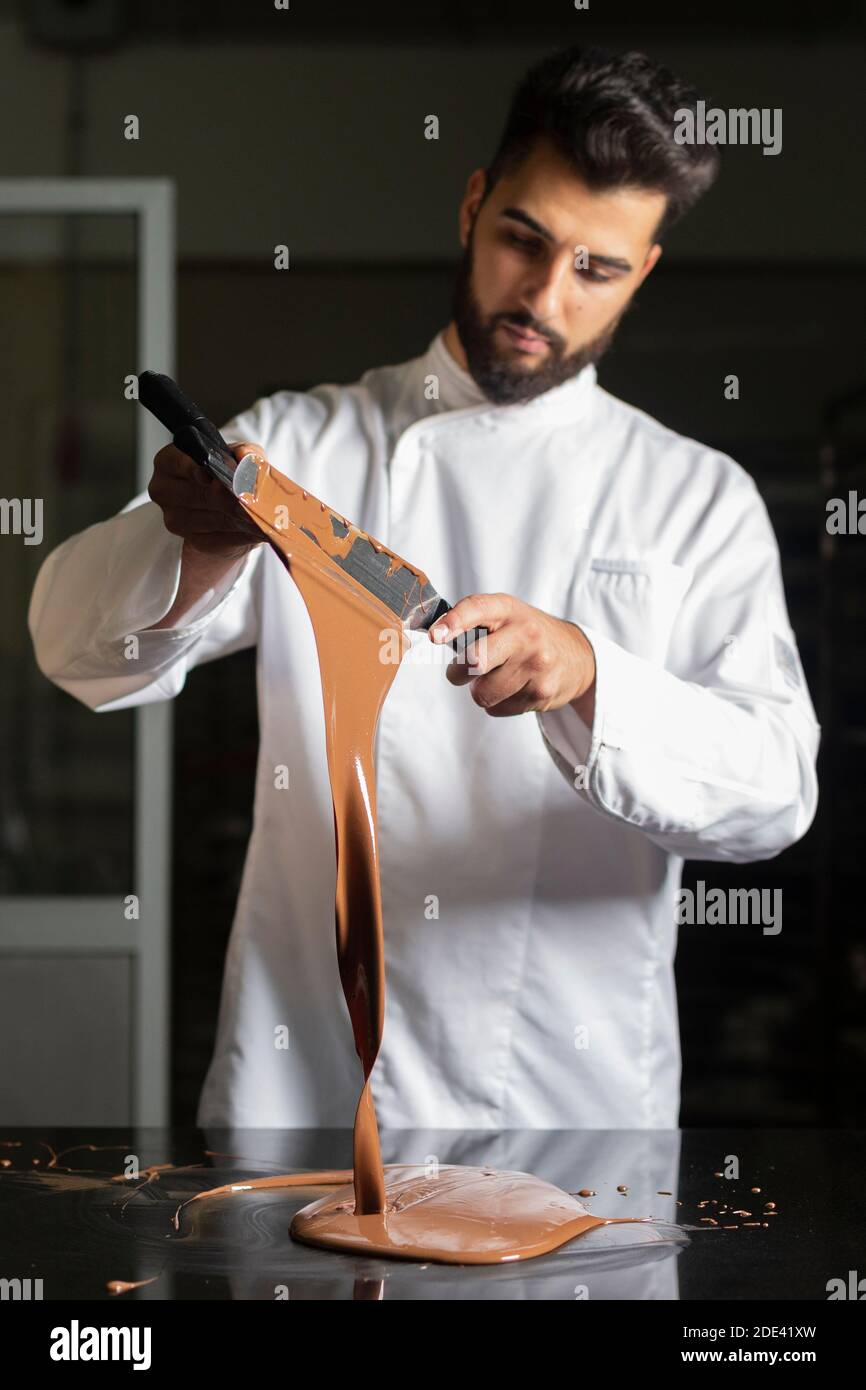 Pastry chef working on tempering chocolate on marble table Stock Photo ...