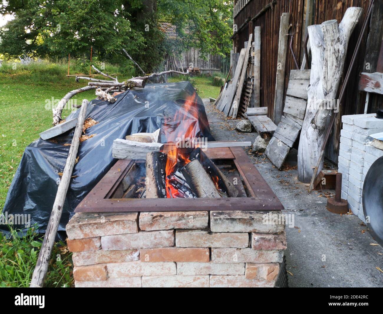 A fire burning in brick charcoal next to a building Stock Photo - Alamy