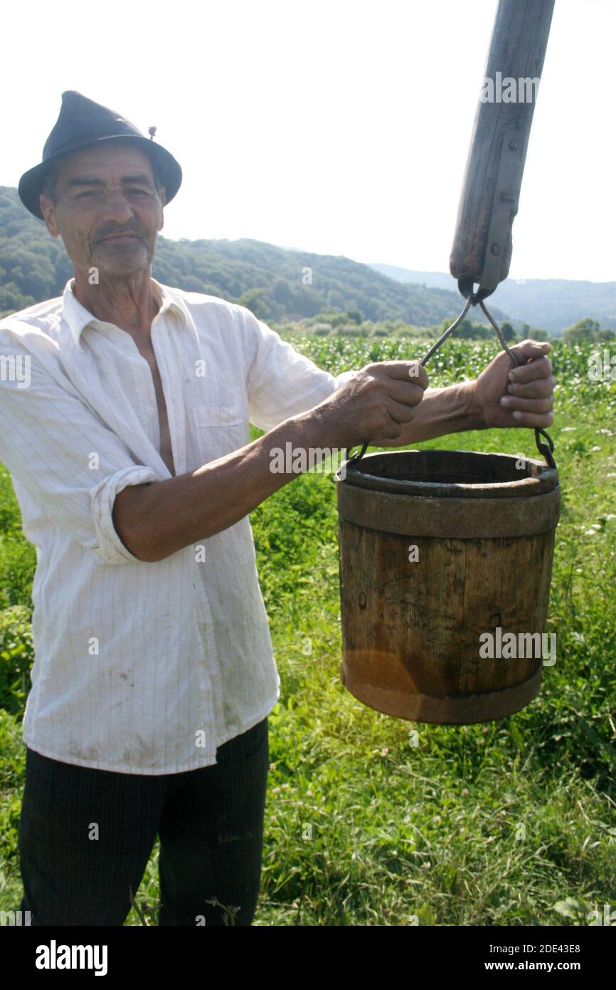 Man in Romania's countryside drawing water from a well Stock Photo - Alamy