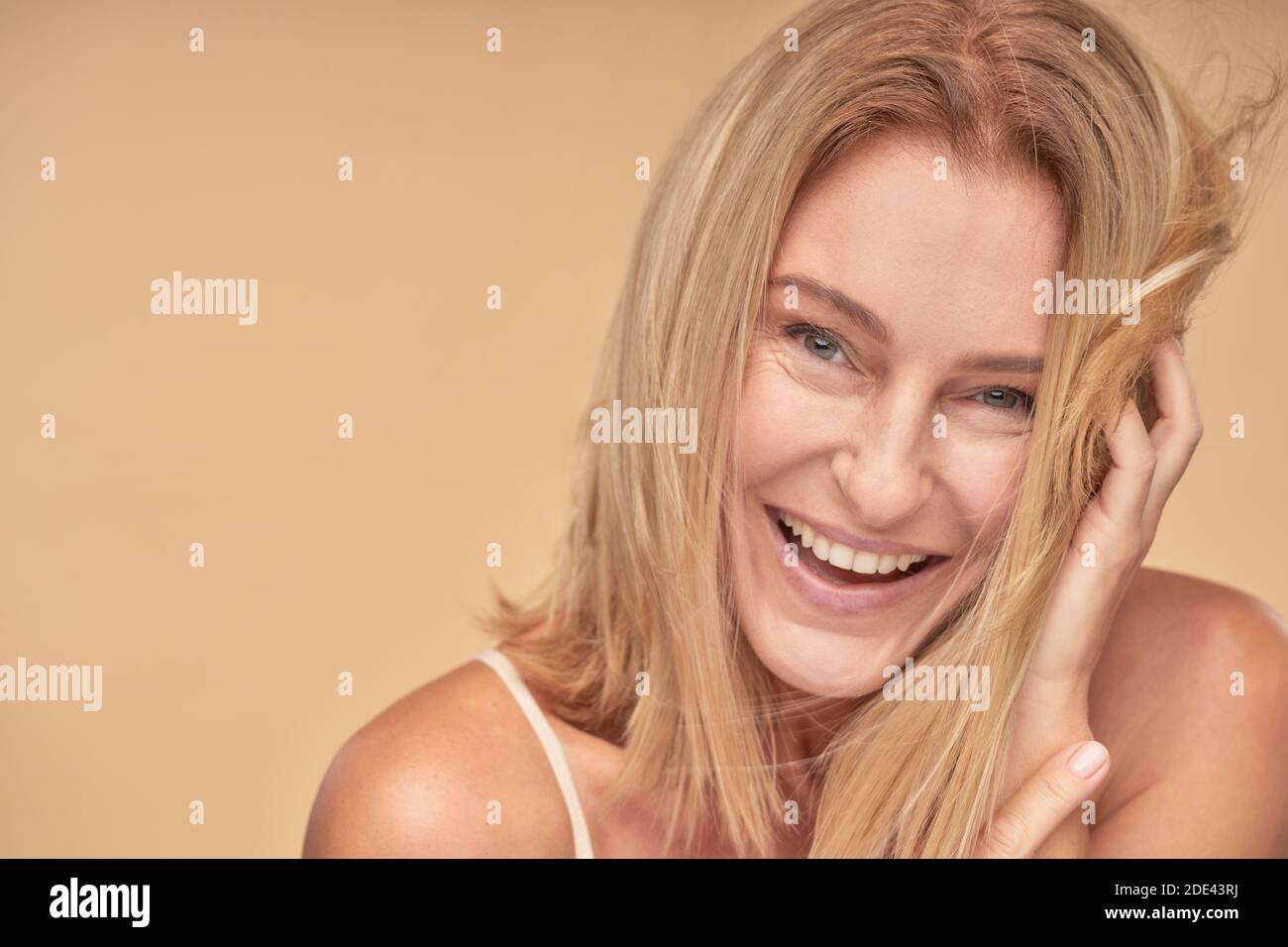 Happy Pretty Mature Woman Posing While Touching Hair By Hands Stock