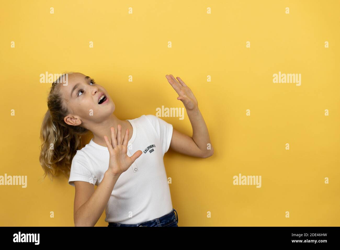 Young beautiful child girl standing over isolated yellow background ...