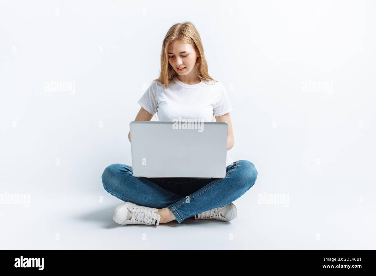 Beautiful girl sitting and typing on laptop, shopping, in Studio Stock ...