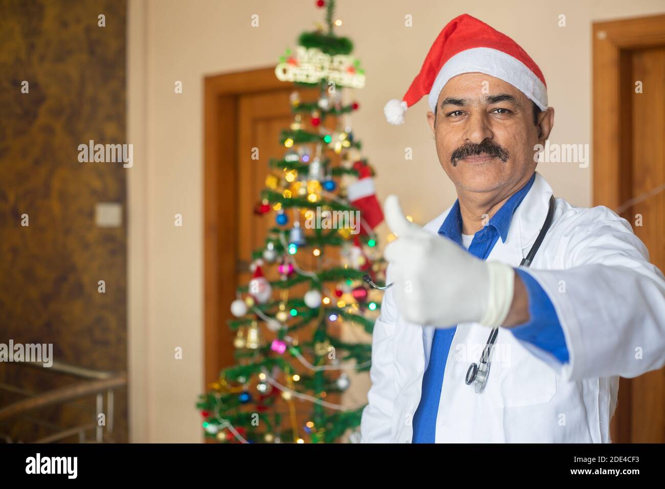 Middle age doctor wearing christmas hat doing thumb up, happy man face ...