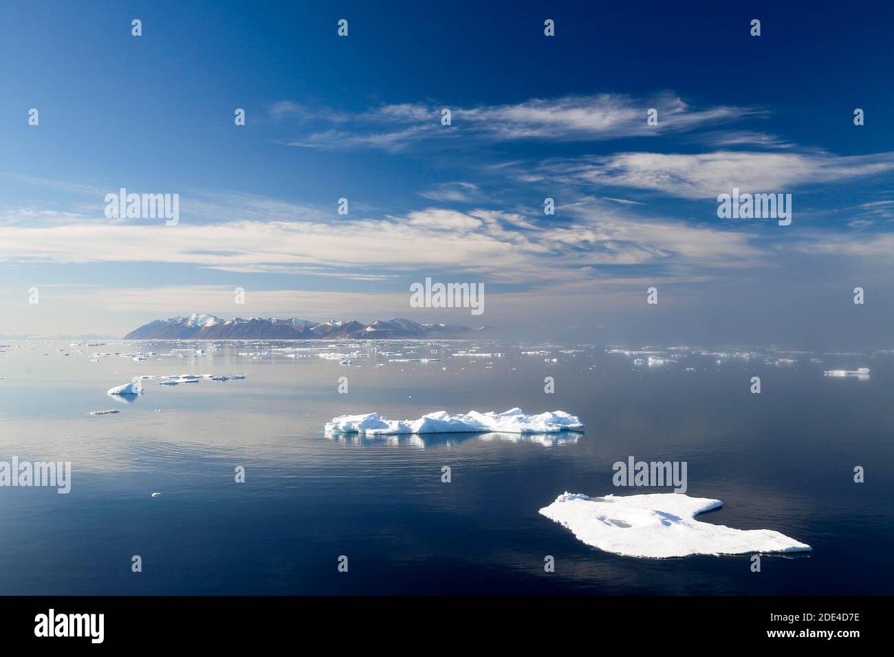 Ice in smooth sea, country in background, east coast Greenland, Denmark ...