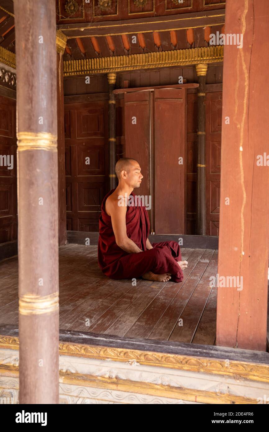 Buddhist monk with red robe meditating in a pagoda, Shwe Hin Thar Monastery, Sagaing, Myanmar ...