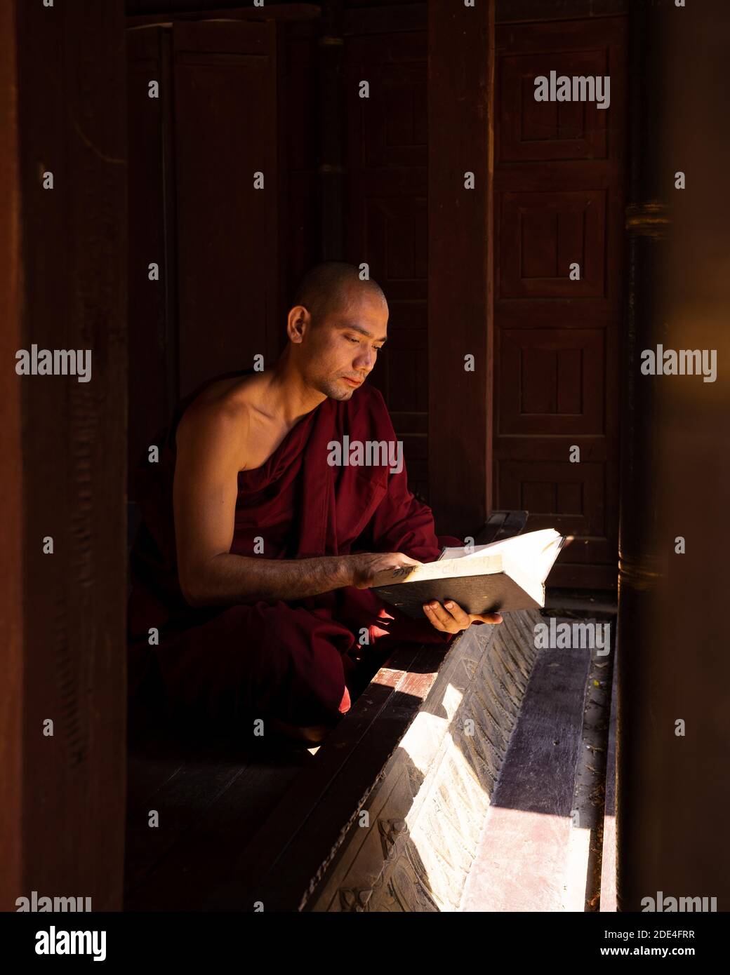 Buddhist monk in red robe reading ancient scriptures in a pagoda, Shwe ...