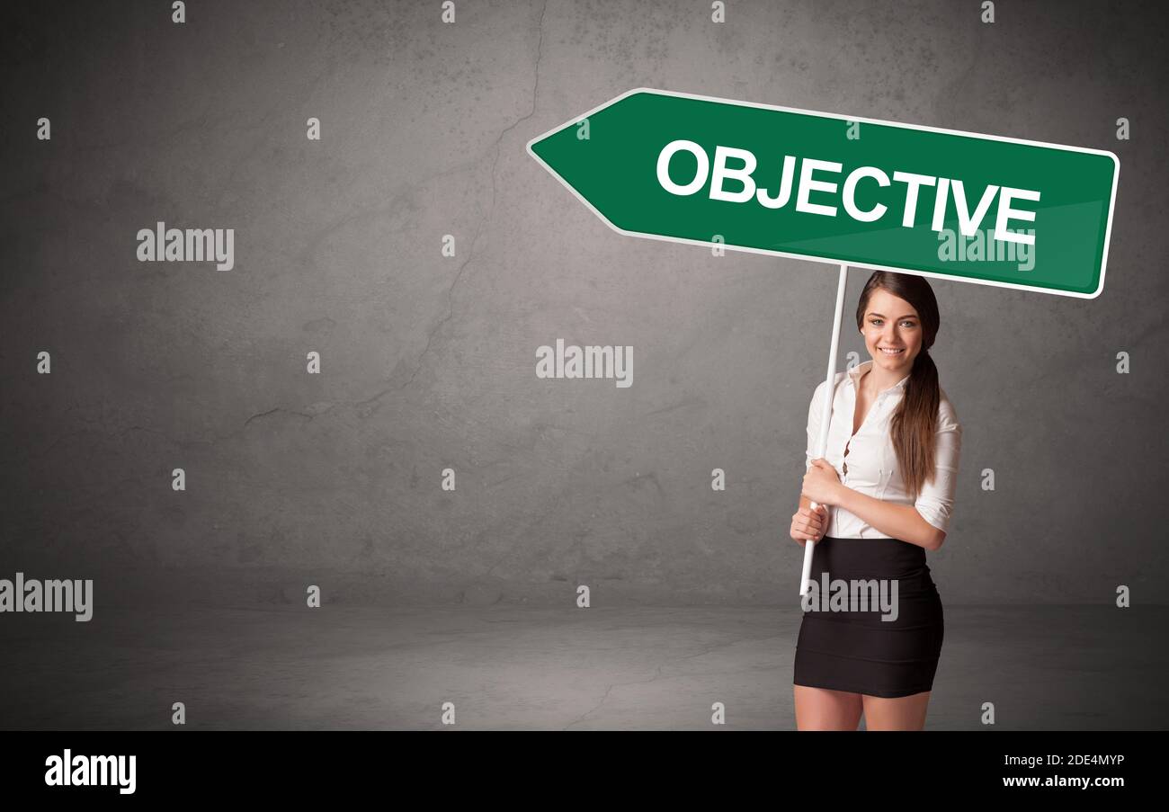 Young business person in casual holding road sign with OBJECTIVE ...