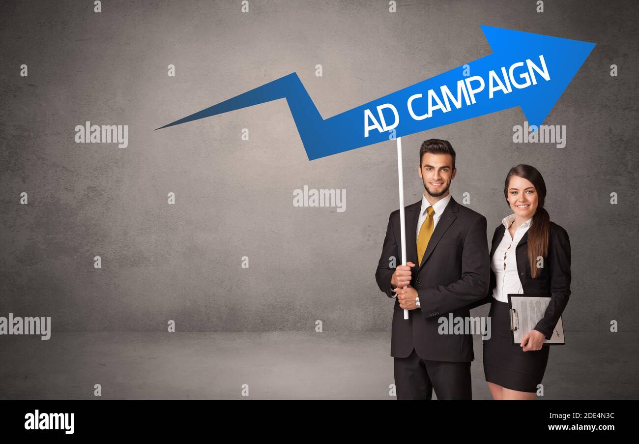 Young business person in casual holding road sign with AD CAMPAIGN ...