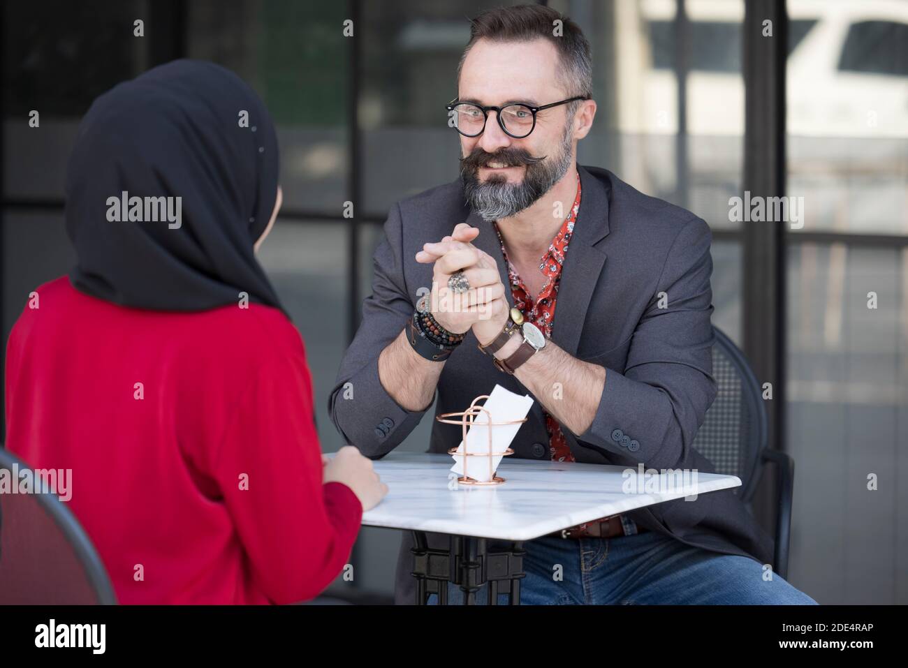 Asian Muslim businesswoman in coffee shop talking to customer or boy ...