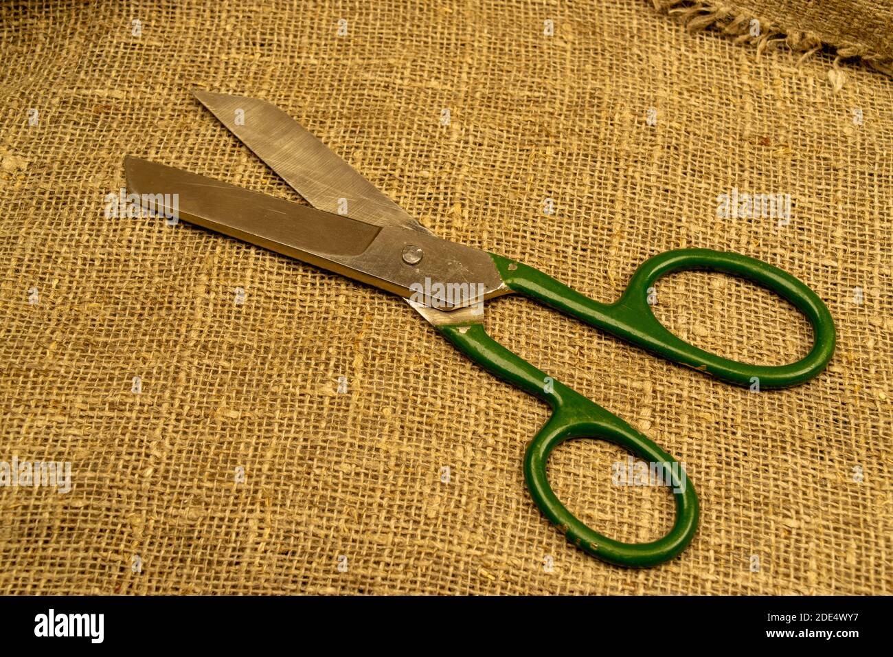 Large vintage scissors lie on rough homespun fabric. Close up Stock ...