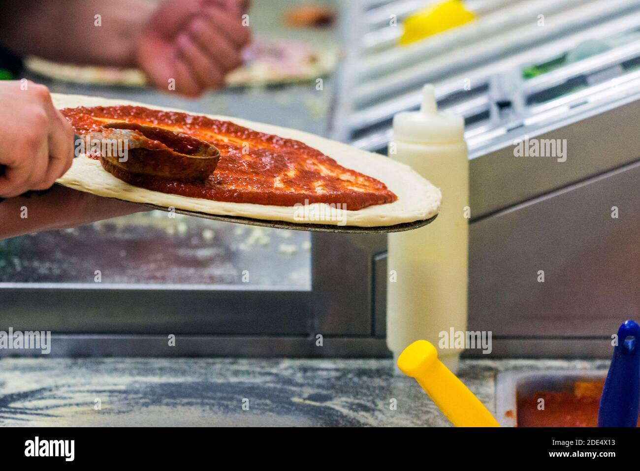 Cook in the kitchen putting the ingredients on the pizza. Pizza concept ...