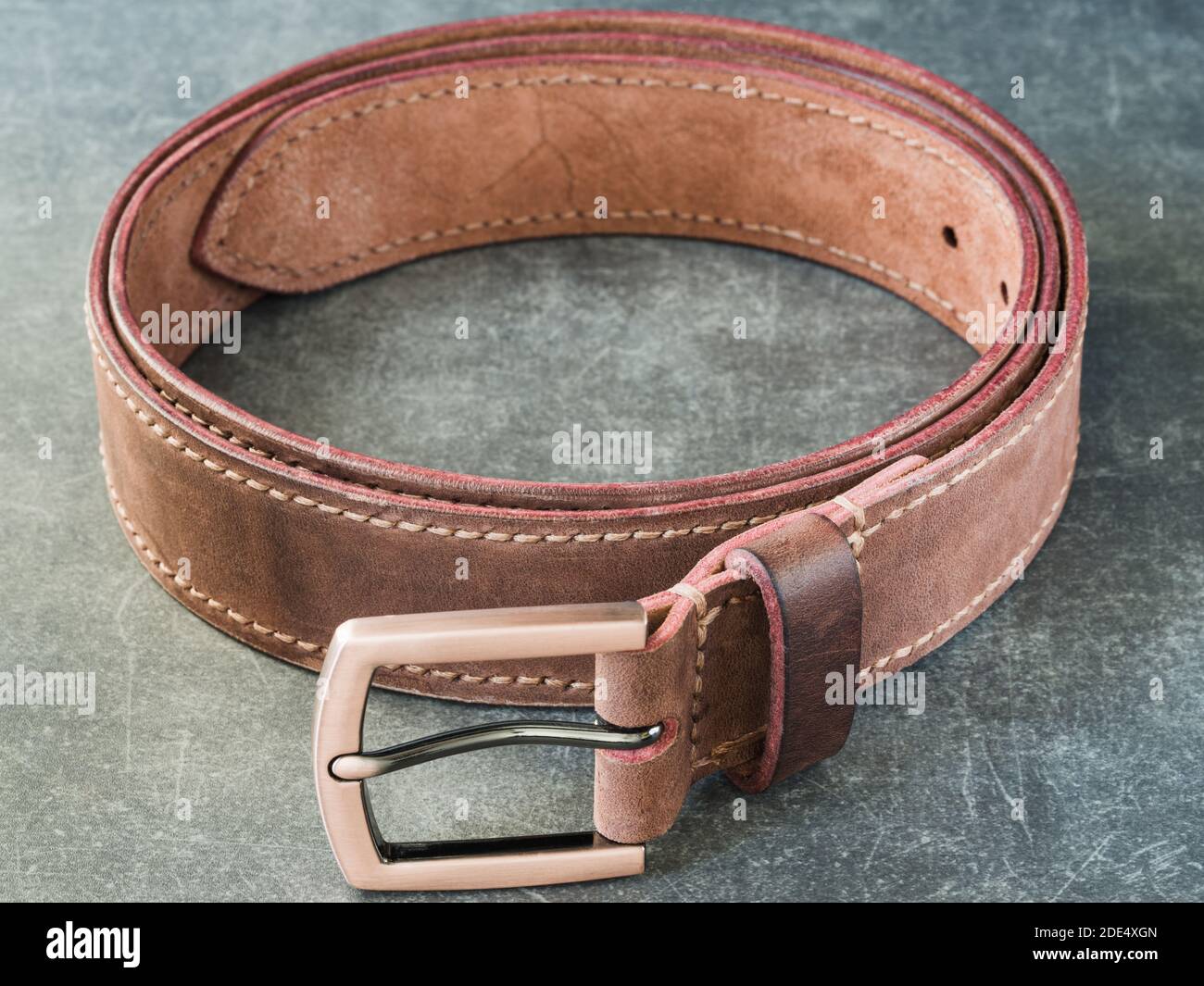leather belt with bronze buckle, part of belt and background is blurred ...