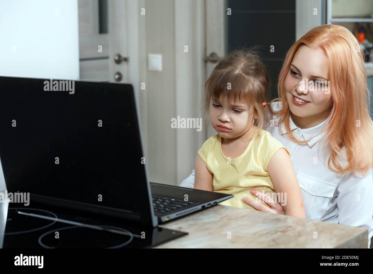 Woman and cute child using laptop. the child is upset and looks at the ...