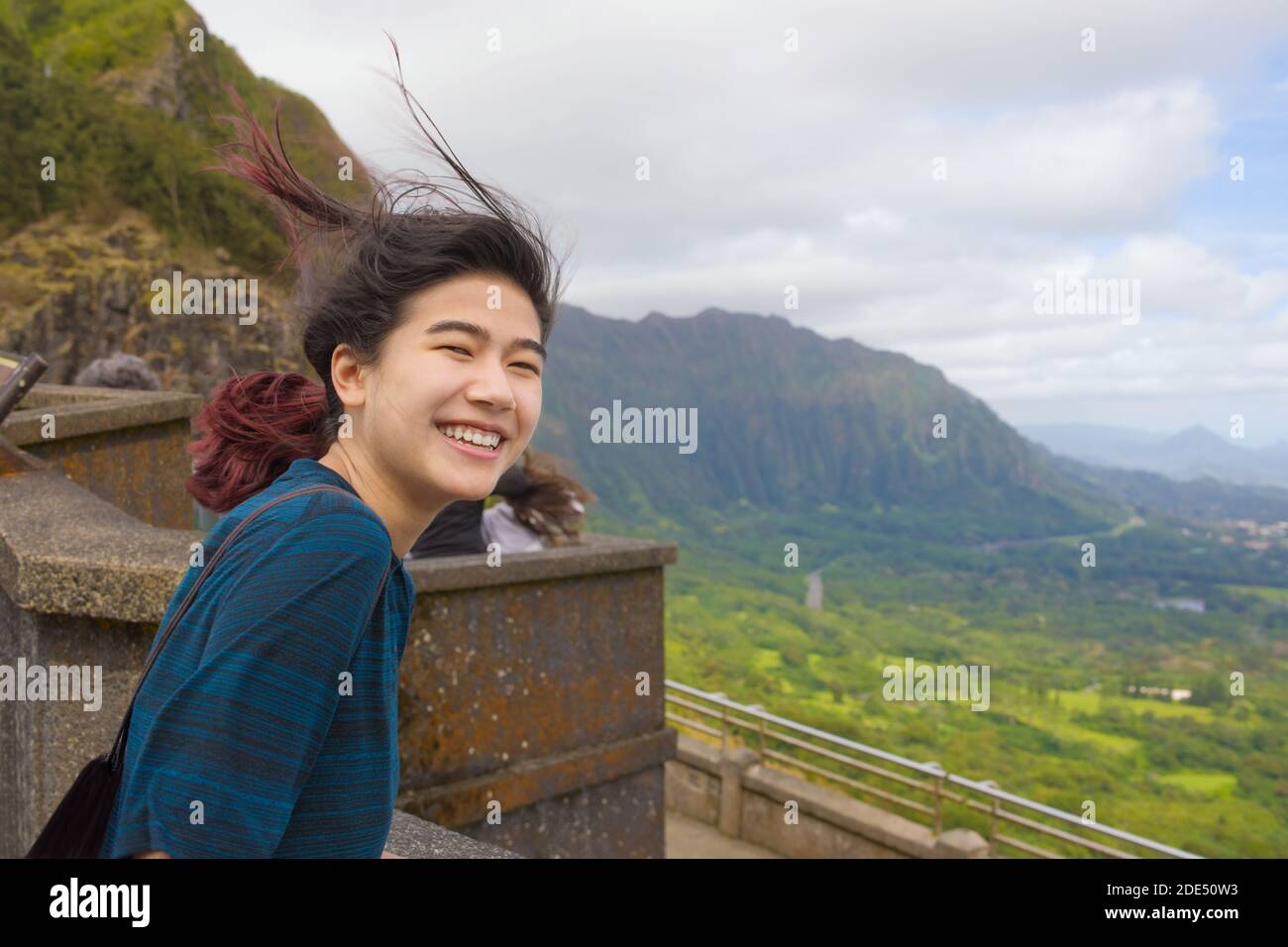 Biracial teen girl standing at Pali lookout and looking out towards the ...