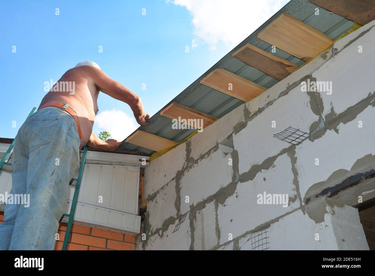 Roofer laying lightweight metal roof tiles on new house rooftop Stock ...