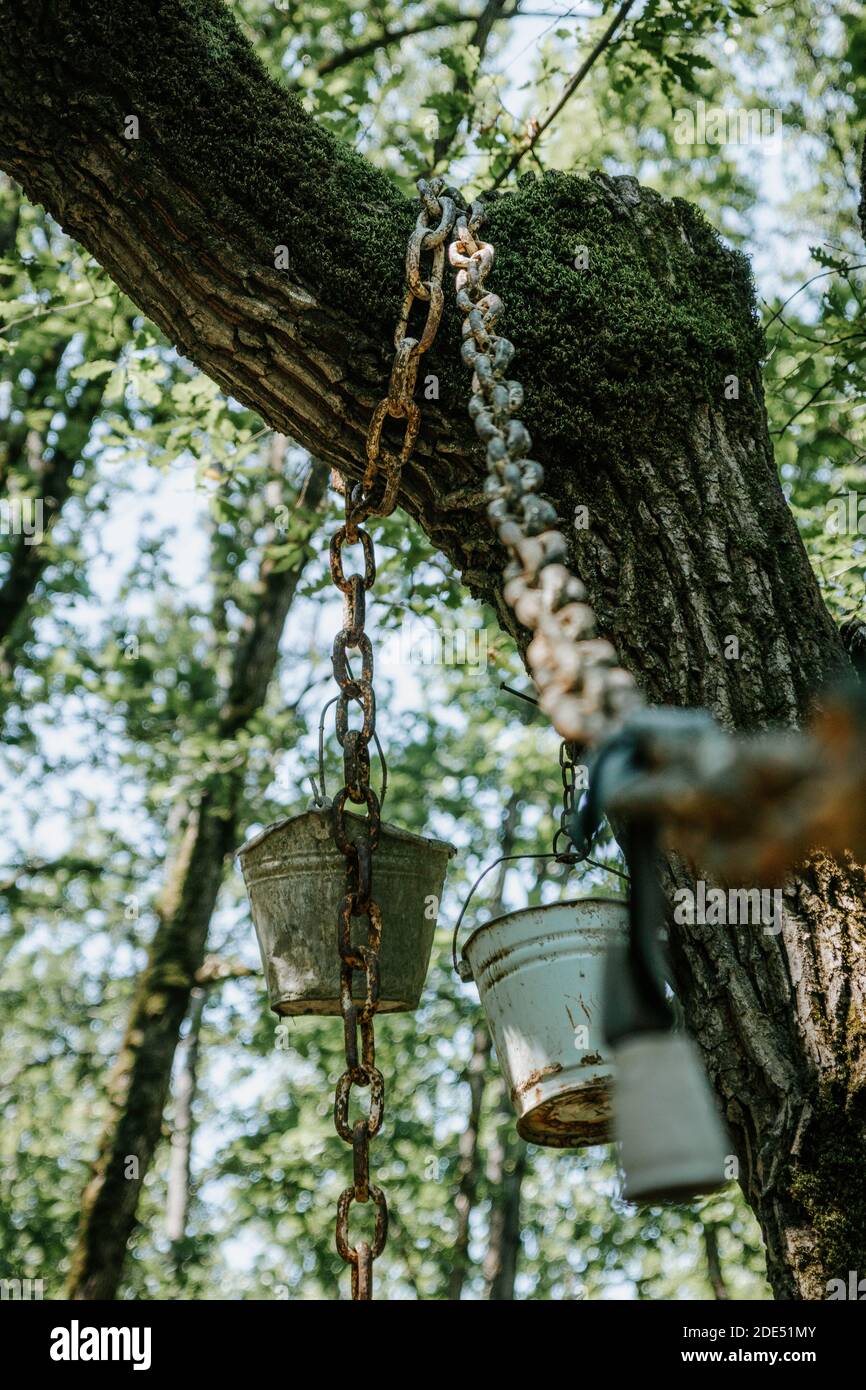 A low angle shot of an old and rustic bucket on a chain hanging on a ...