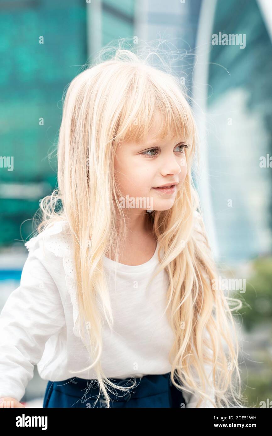 portrait of a beautiful blonde kid girl in a white blouse against the ...