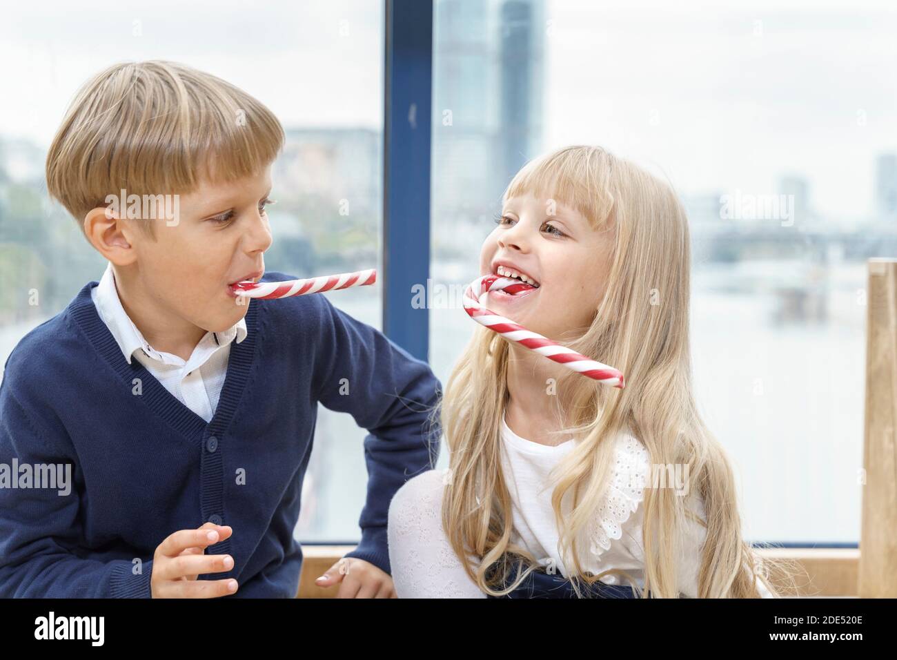 Two children joyful playing with candy cane struggle game Stock Photo ...