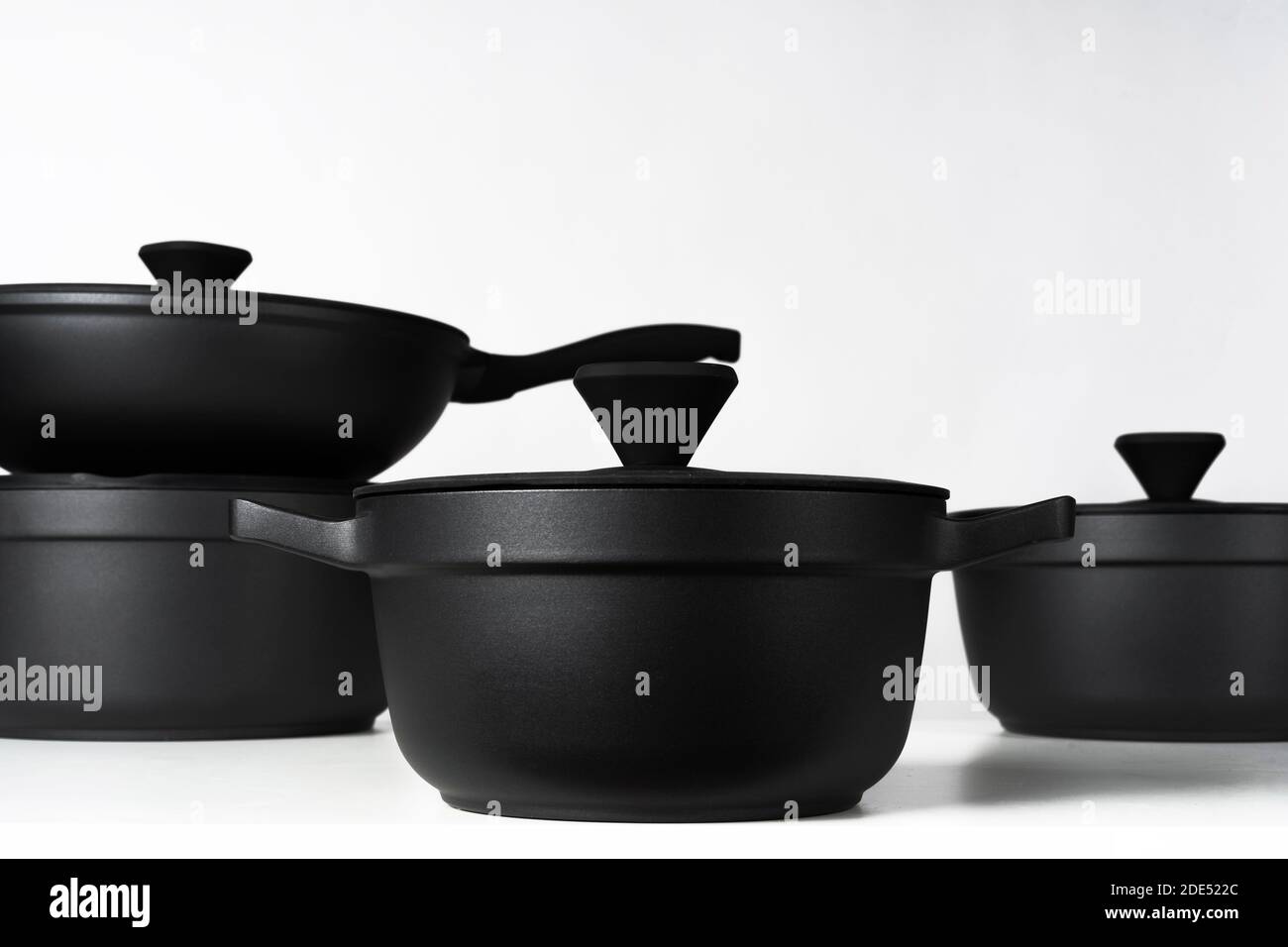 Black cooking pots on grey background front view Stock Photo - Alamy