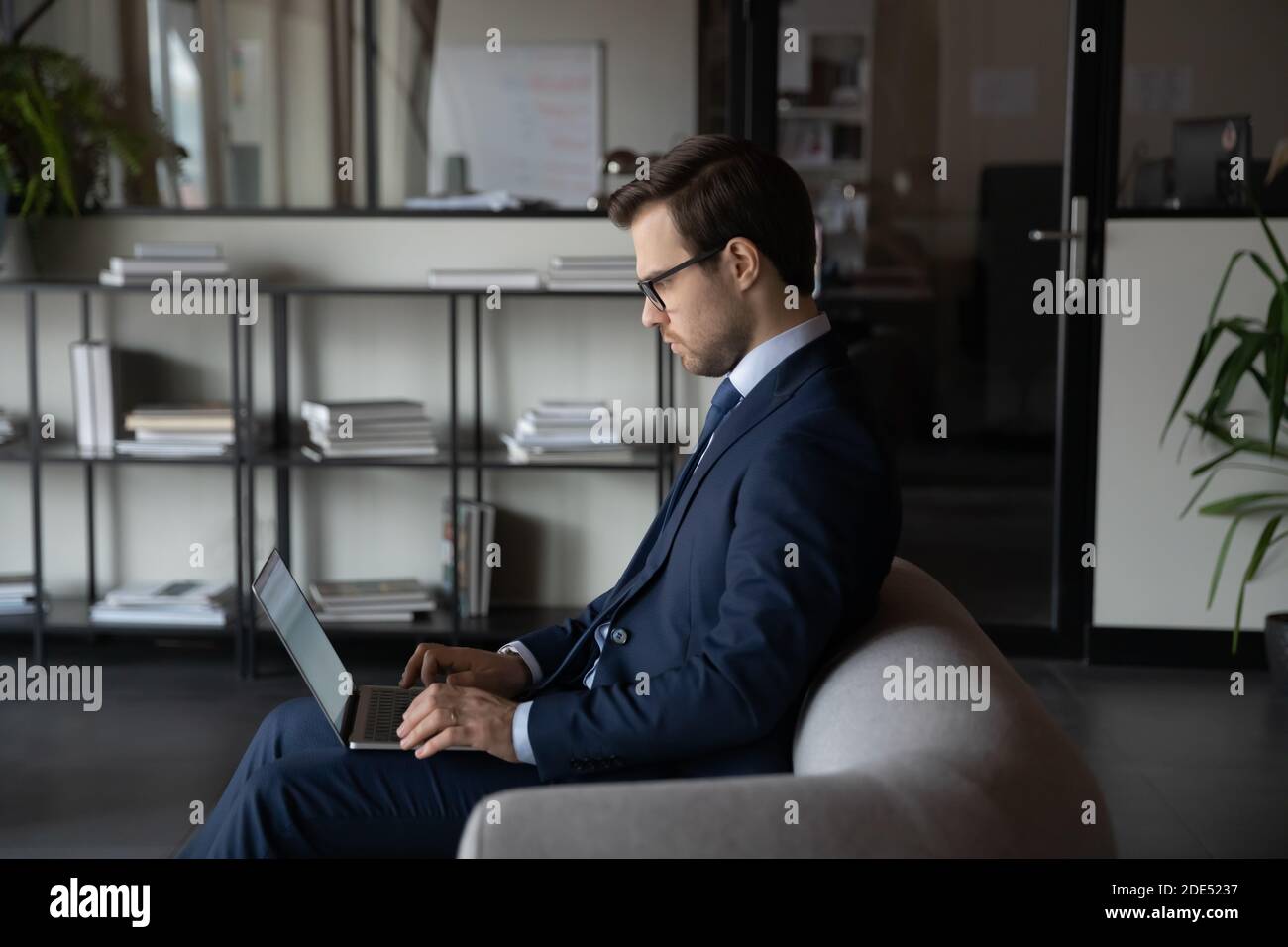 Busy male employee using laptop on sofa at coworking space Stock Photo ...