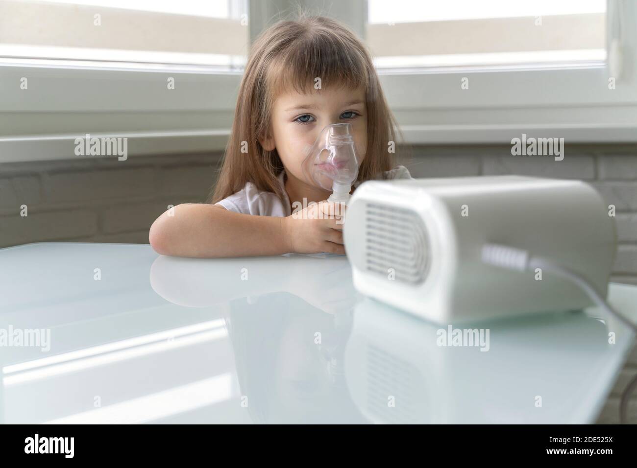 little girl is being treated with a nebulizer at home. pneumonia ...