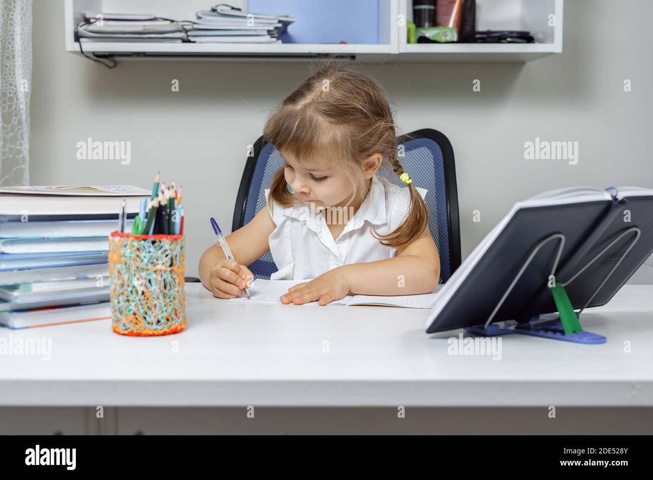 little girl doing homework at the table Stock Photo - Alamy