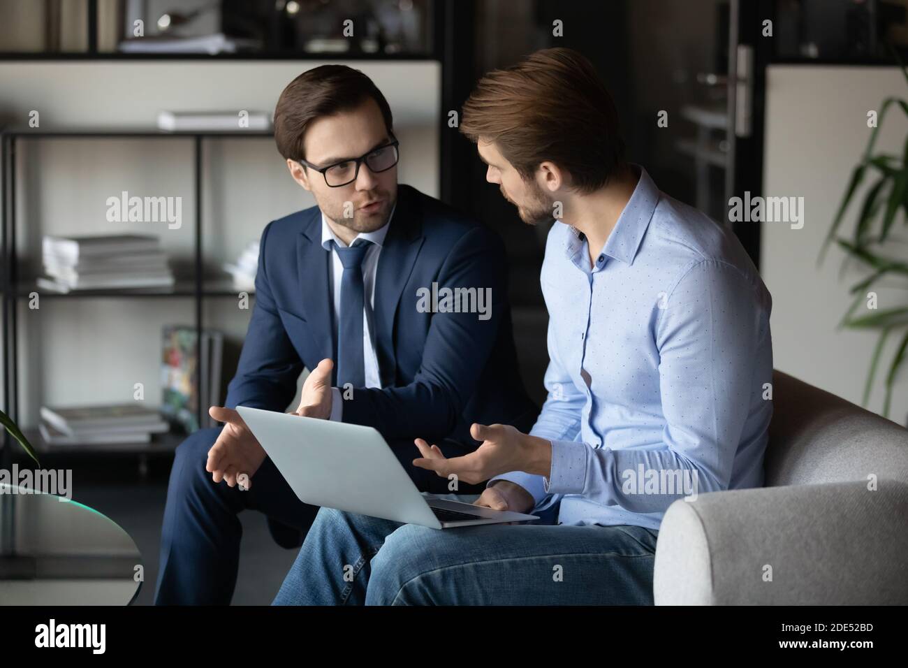 Young male manager explaining client contract details on laptop screen ...