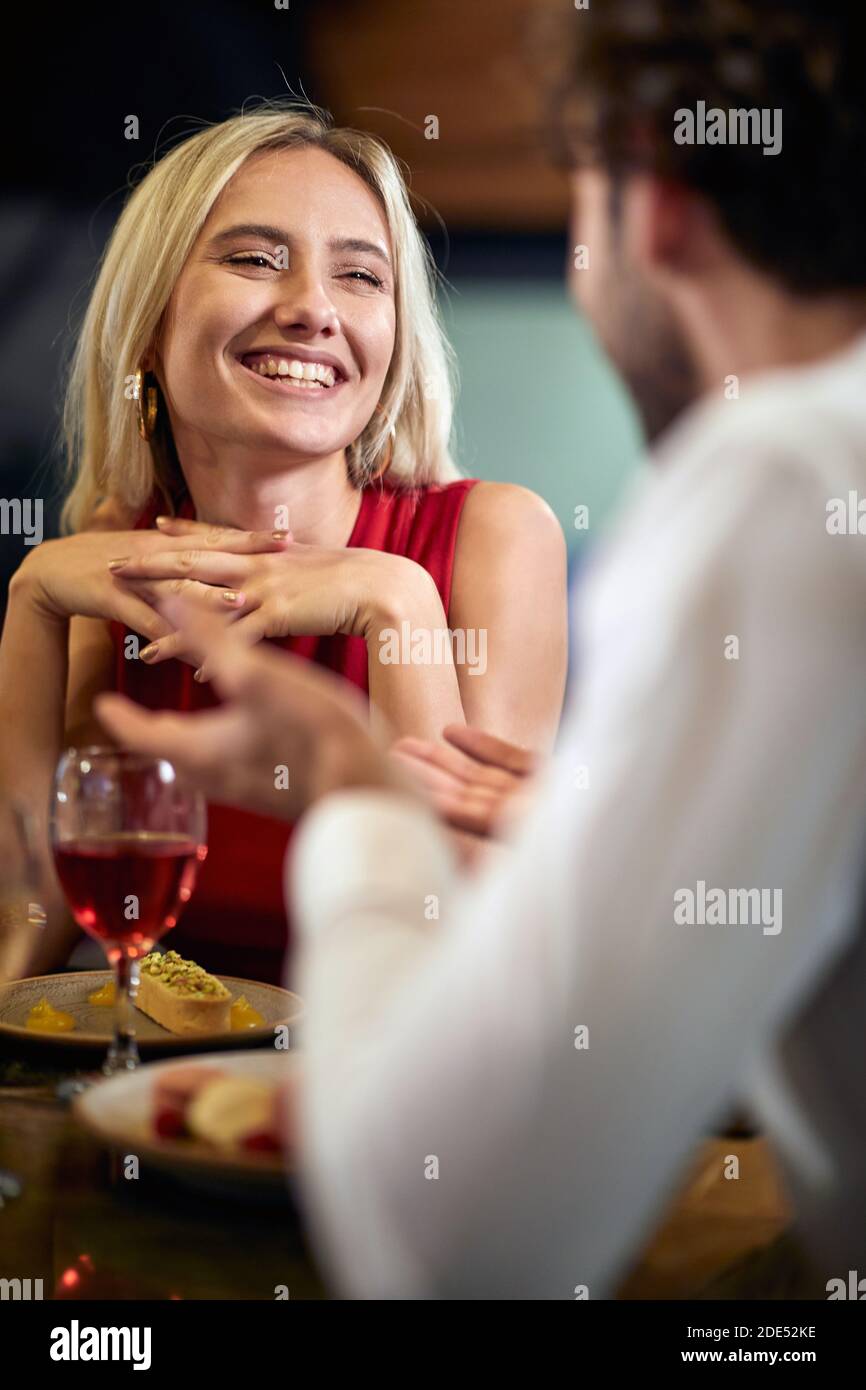 young caucasian blonde smiling, charmed by her partner at dinner. in ...