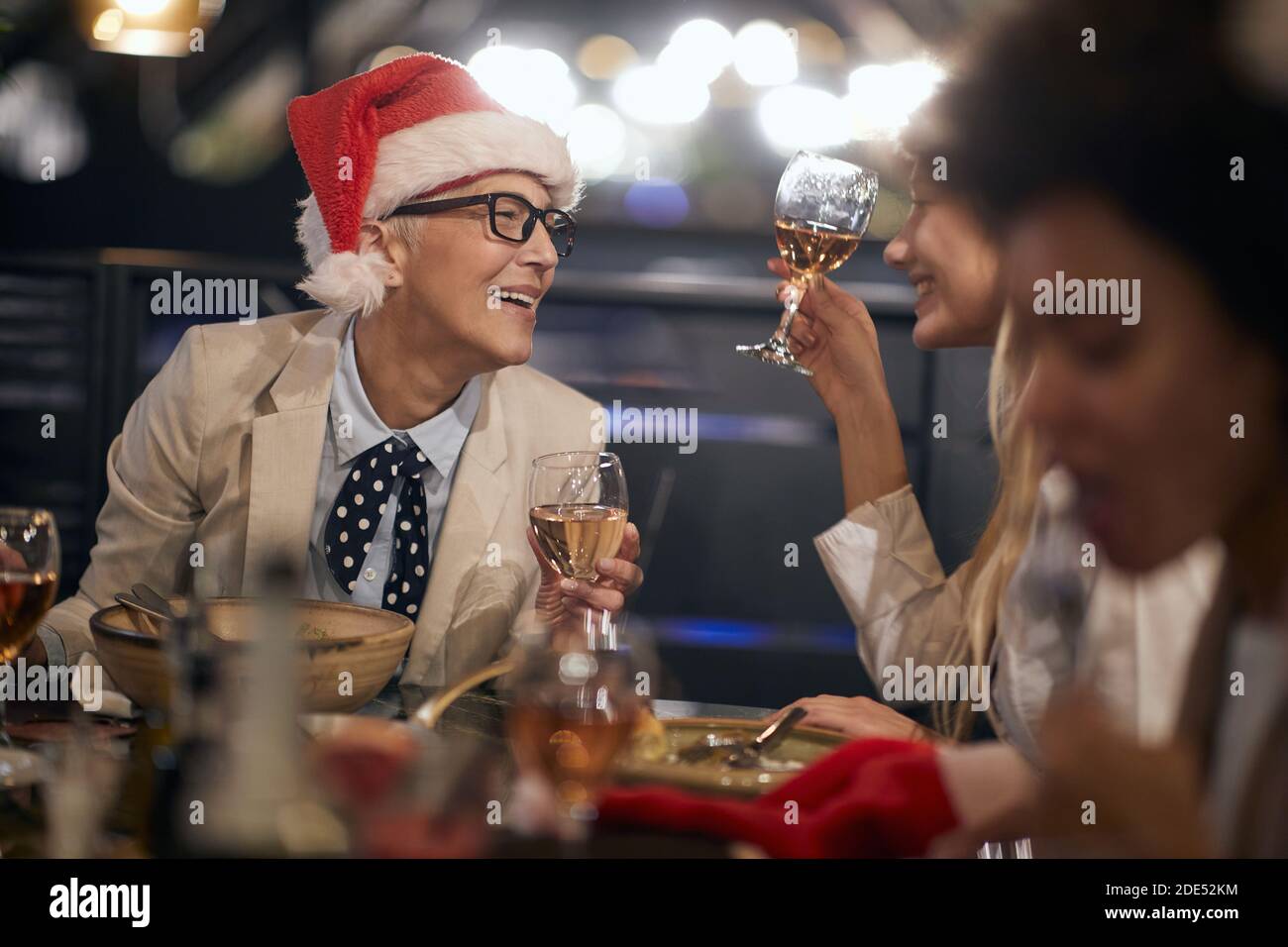 caucasian boss lady wearing santa hat with glasses having a good time ...