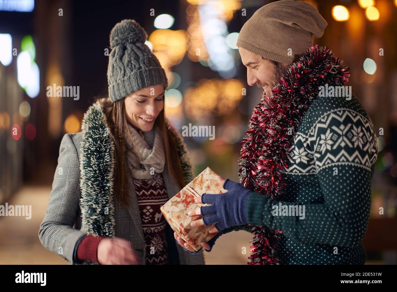 A boyfriend giving a Christmas present to his girlfriend while walking ...