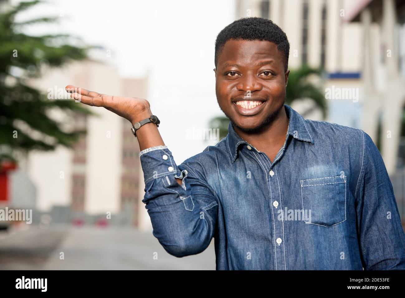 portrait of young happy man in shirt gesturing a welcome sign showing ...