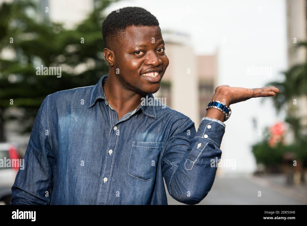 portrait of young happy man in shirt gesturing a welcome sign showing ...