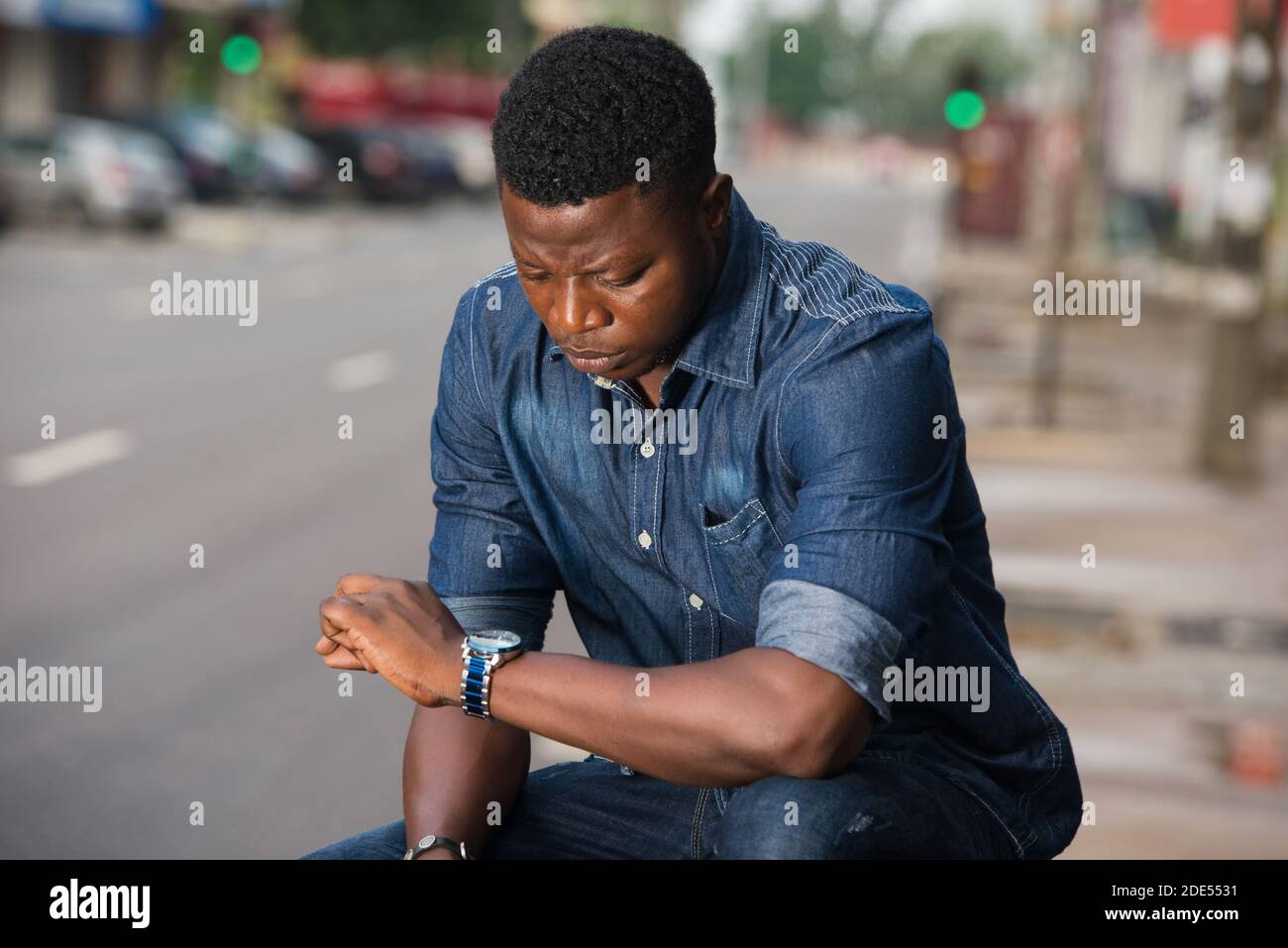 young man with serious face watches watch in hand waiting for a late ...
