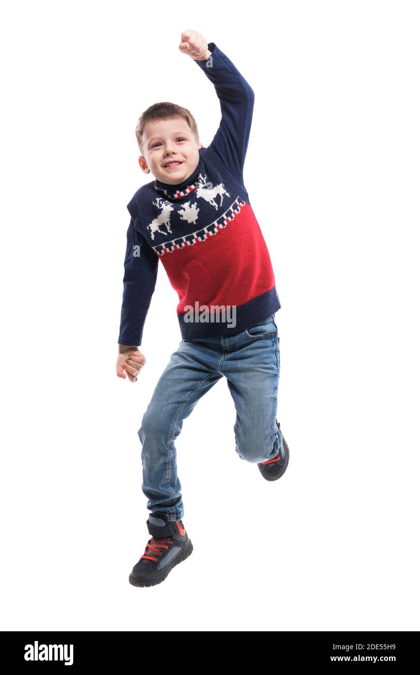 Joyful little kid jumping excited in Christmas jumper looking up with ...