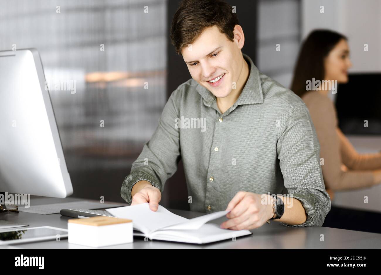 Smiling young businessman and programmer in a green shirt is flipping ...