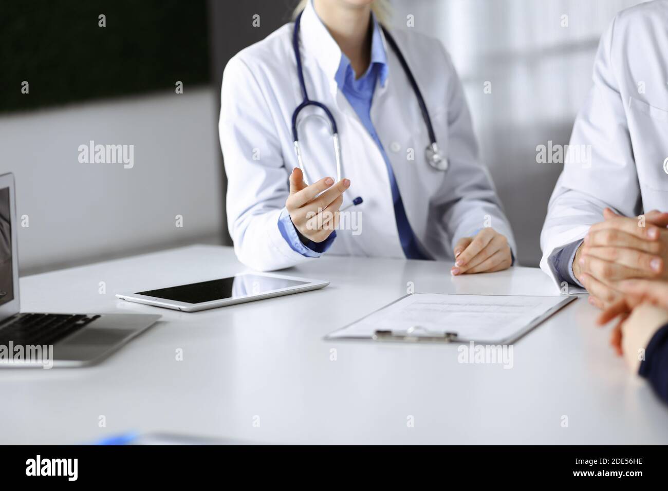 Two doctors and patient woman discussing something while sitting at the ...