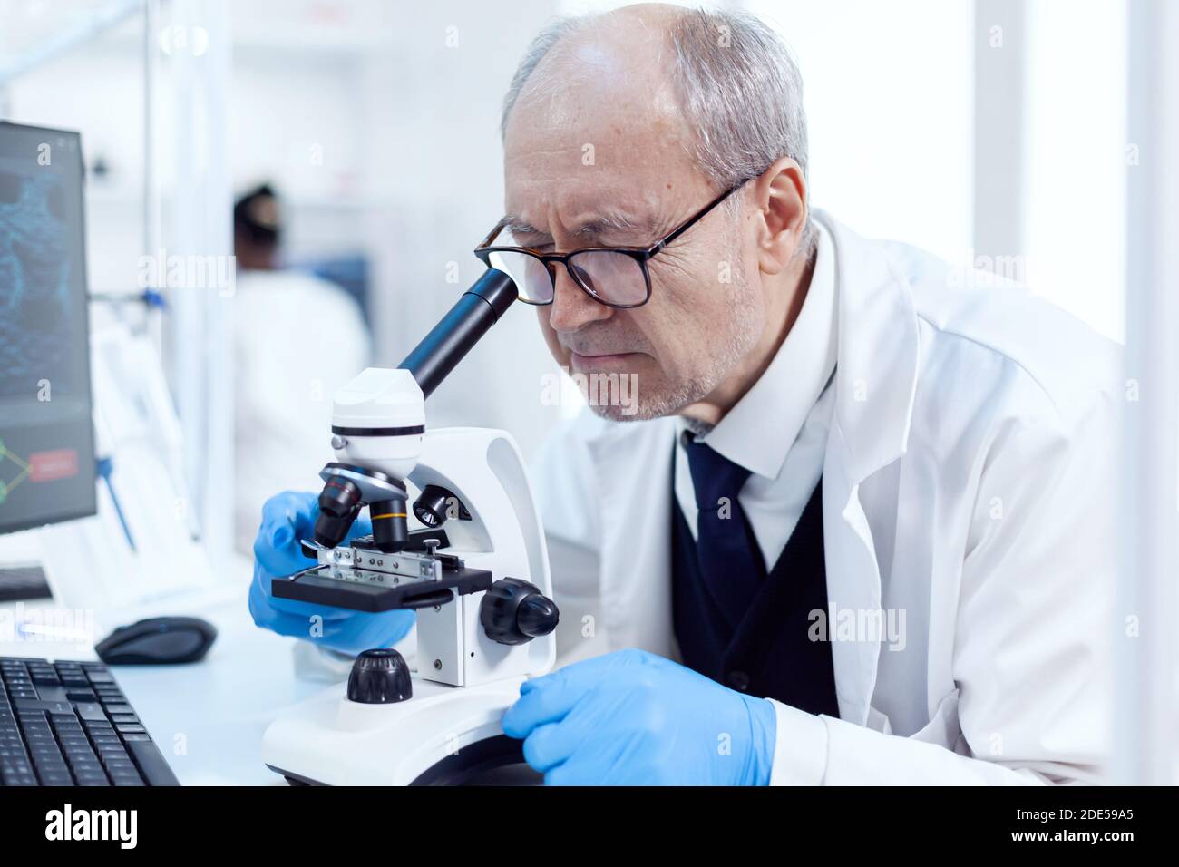 Senior scientist working on busy laboratory using modern microscope ...