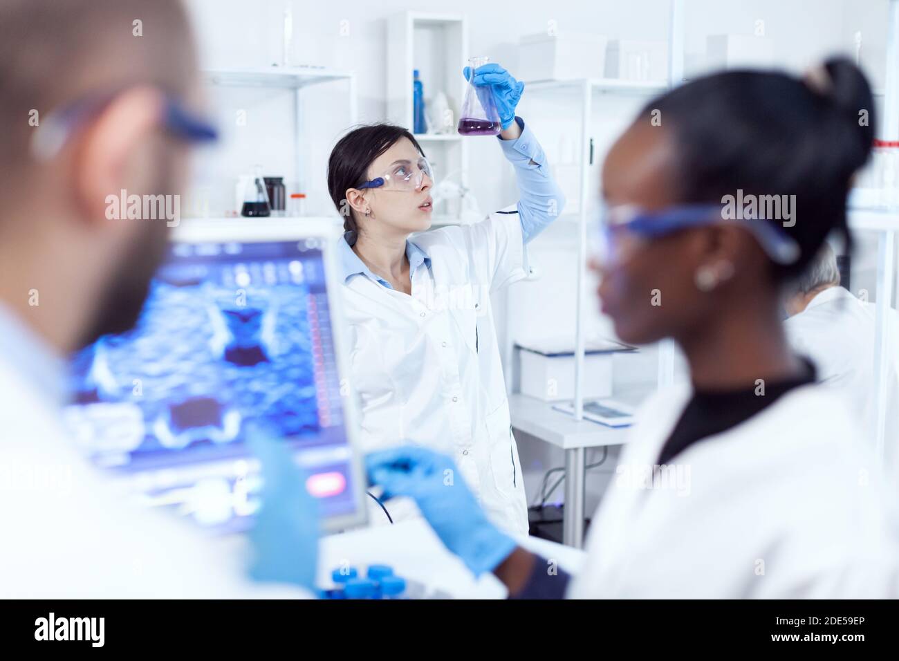 Chemistry exppert looking at scientific sample in busy laboratory ...