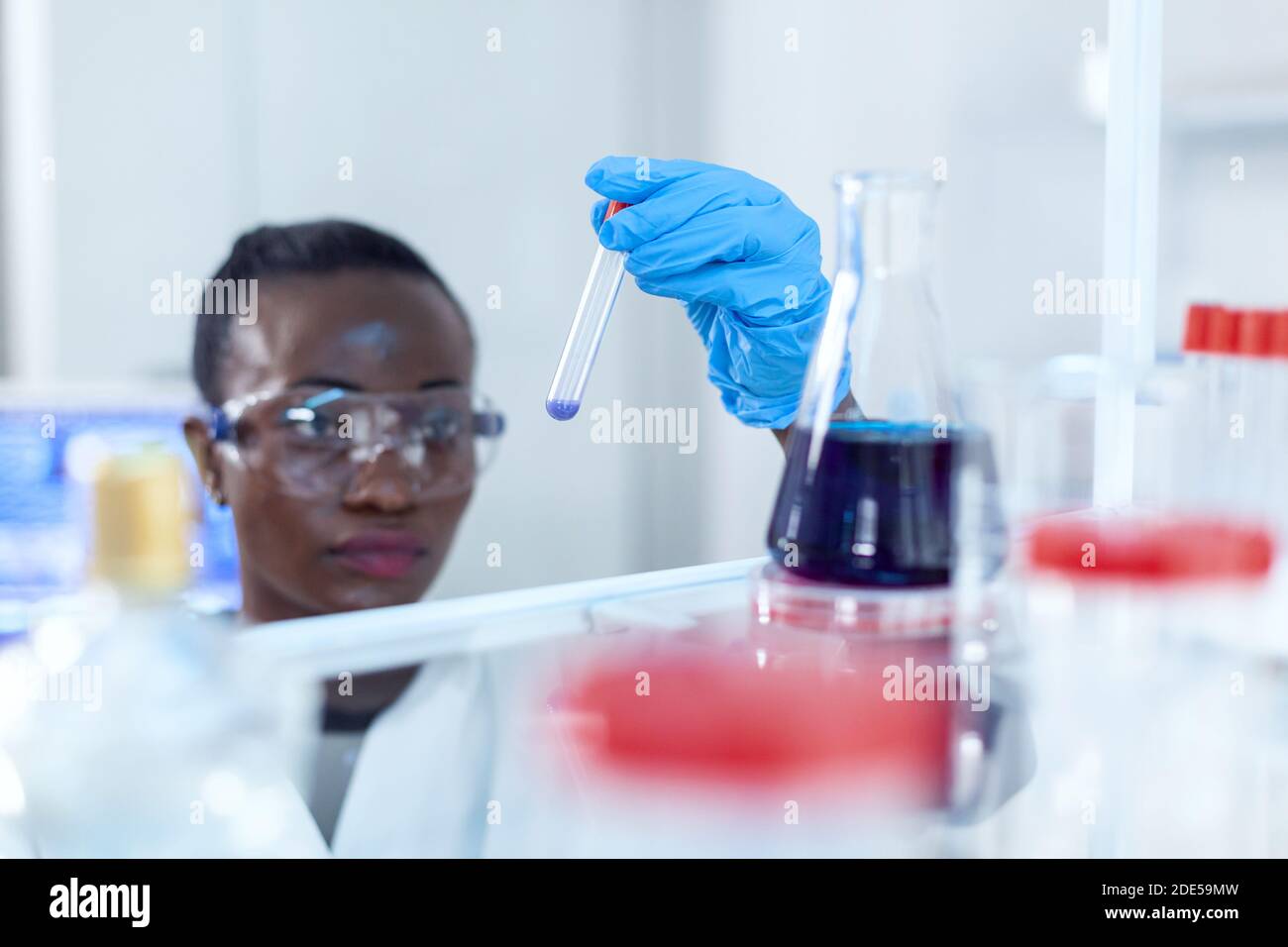 African scientist staring at sample blue liquid in test tube chemical ...