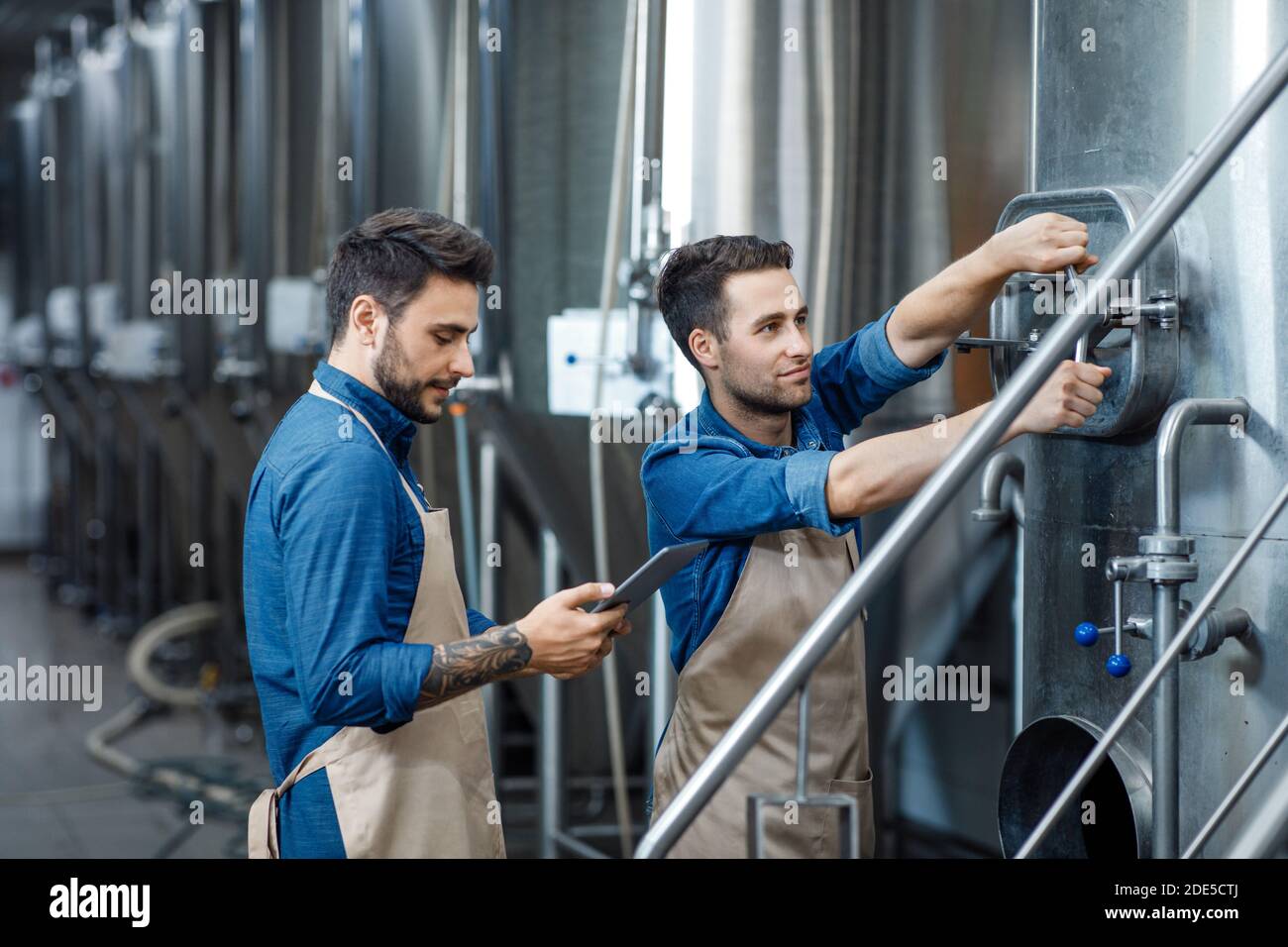 Worker in uniform looking at tablet standing in drink factory Stock ...