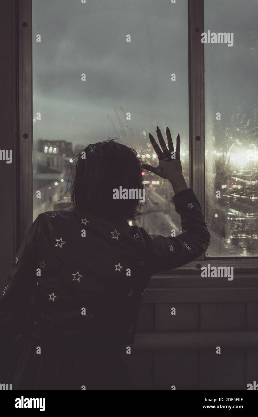 a Halloween scary zombie girl standing with her back and watching ...