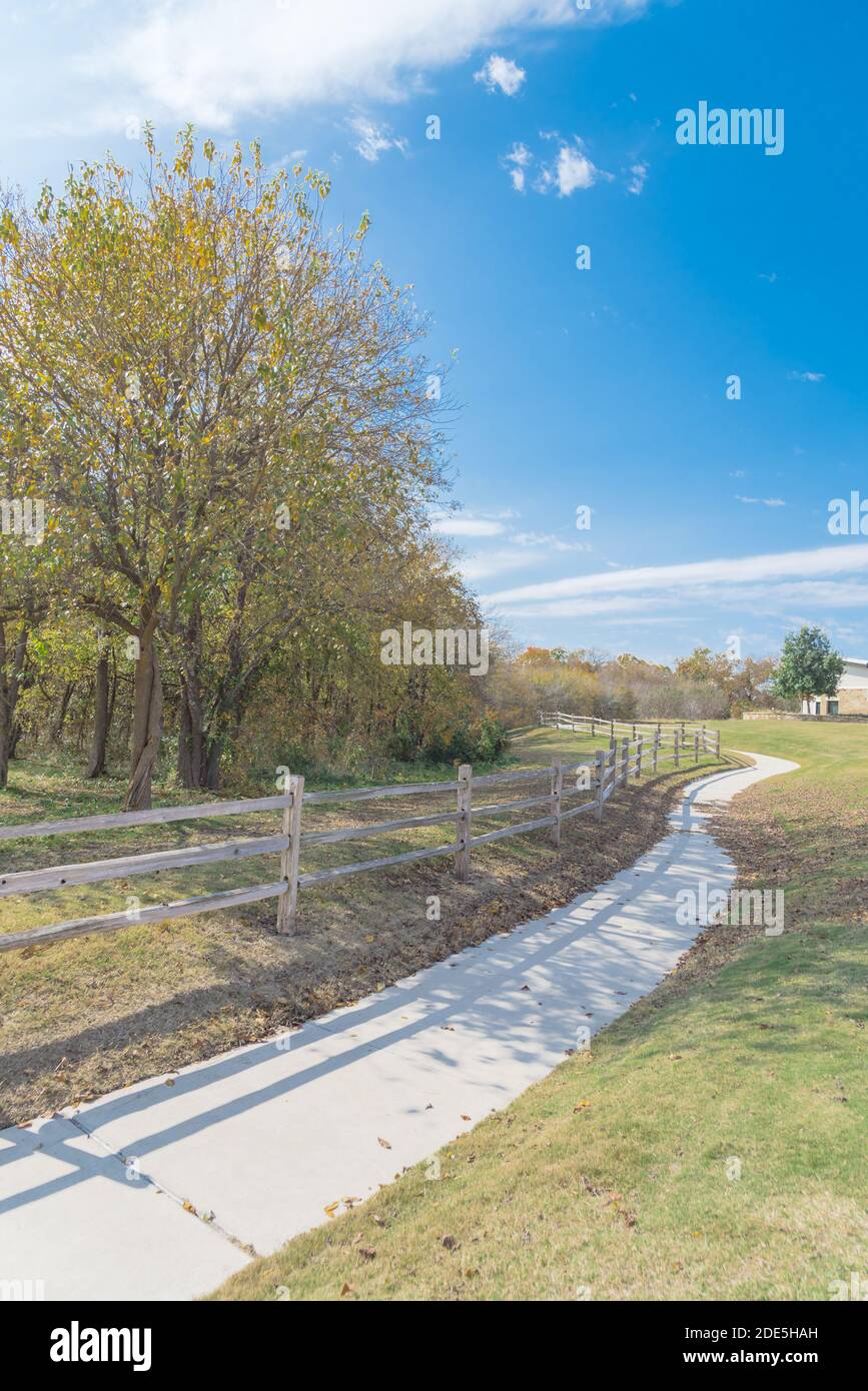 Long curved concrete pathway with rustic wooden fence and colorful fall ...