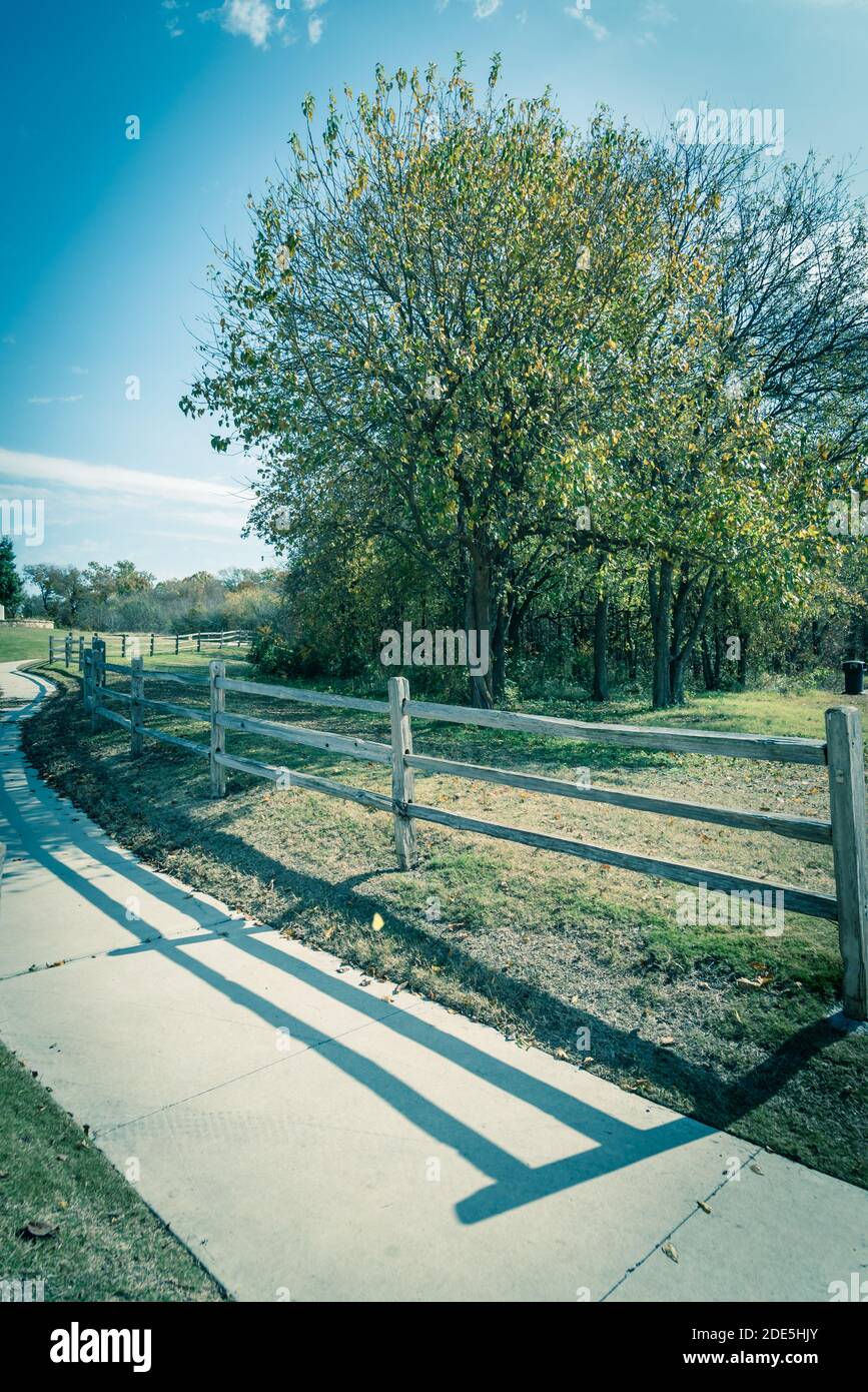 Long curved concrete pathway with rustic wooden fence and colorful fall ...