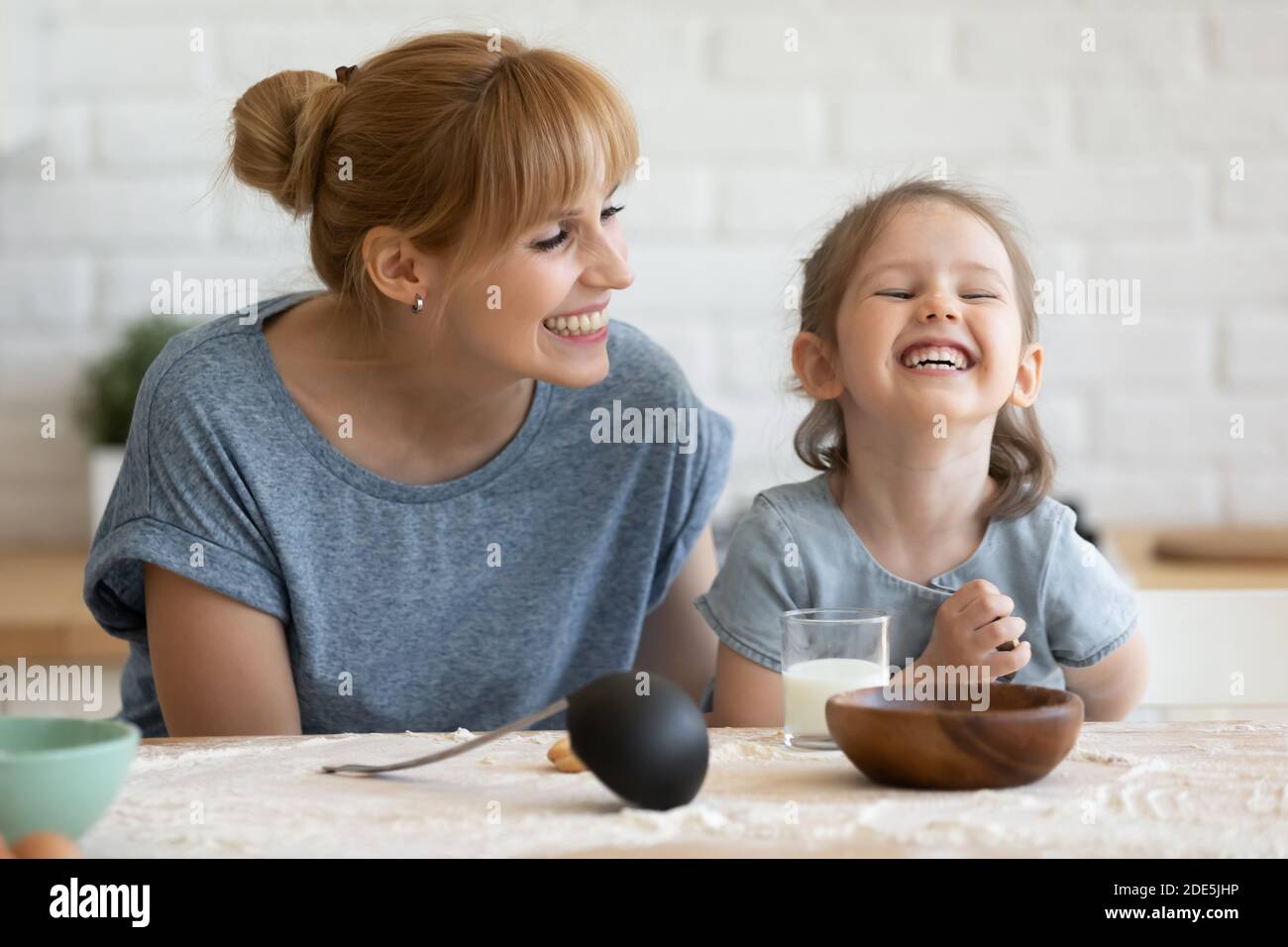 Overjoyed mother and little daughter eating homemade cookies, having ...