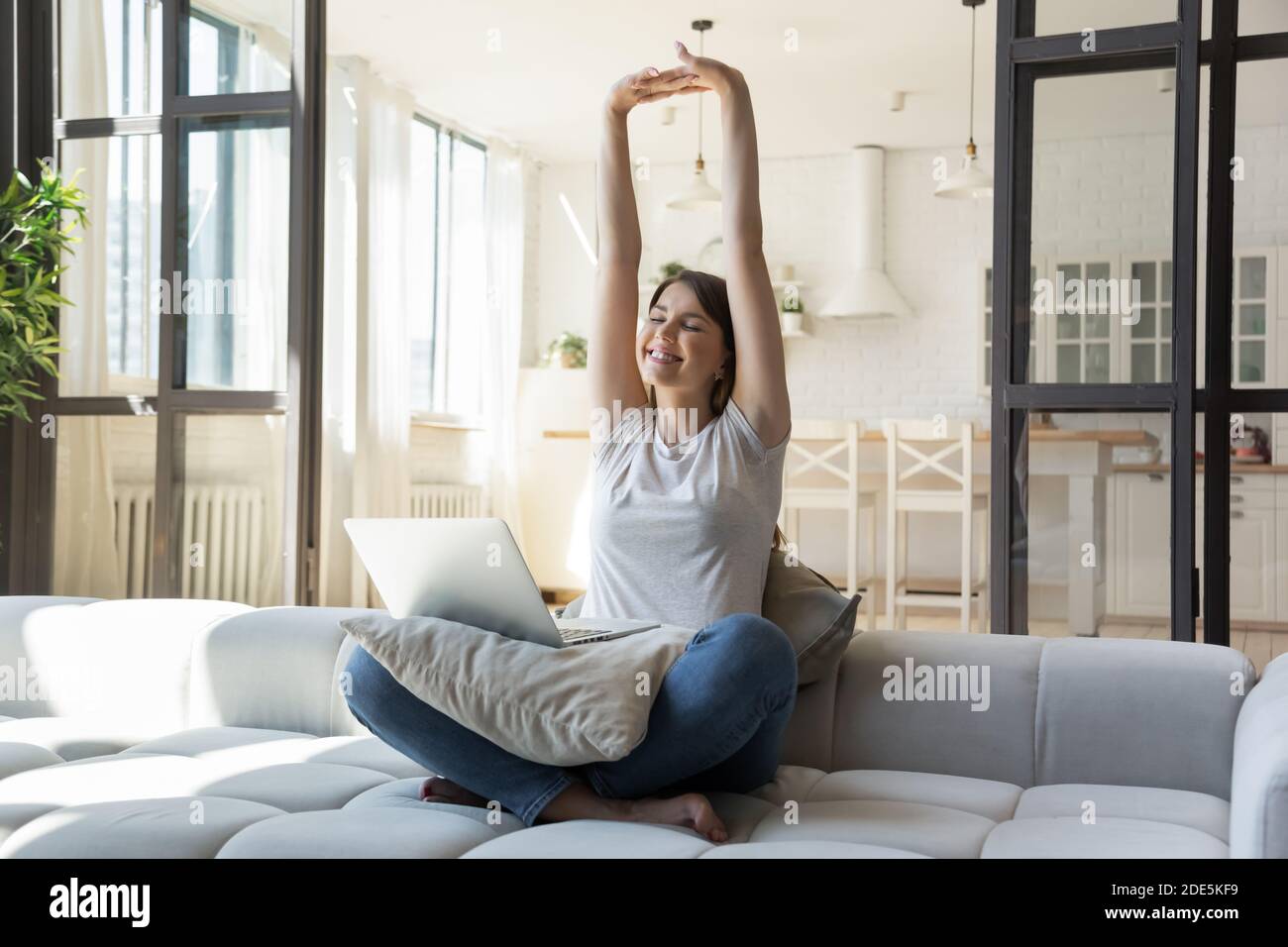 Happy young woman stretching, relaxing after work done, using laptop ...
