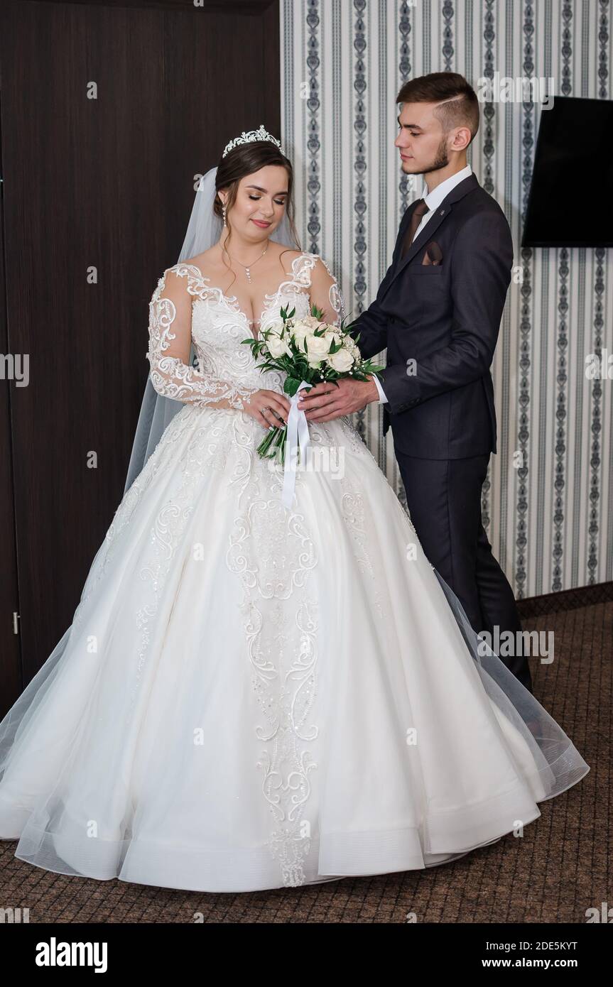 the groom looks at the bride and holds hands in the hotel room Stock ...