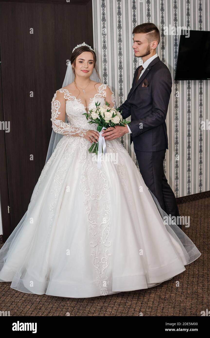 the groom looks at the bride and holds hands in the hotel room Stock ...
