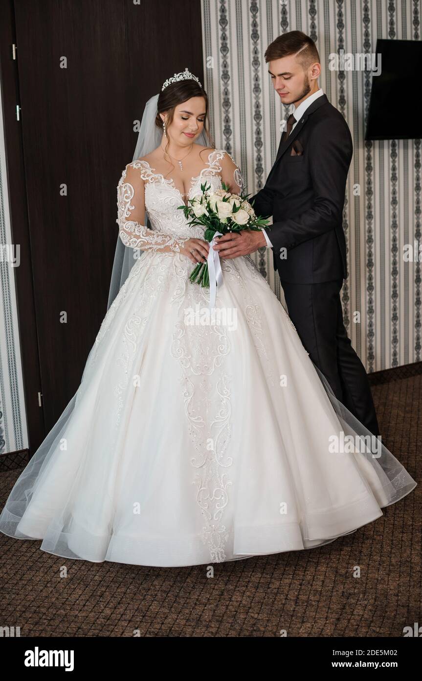 the groom looks at the bride and holds hands in the hotel room Stock ...